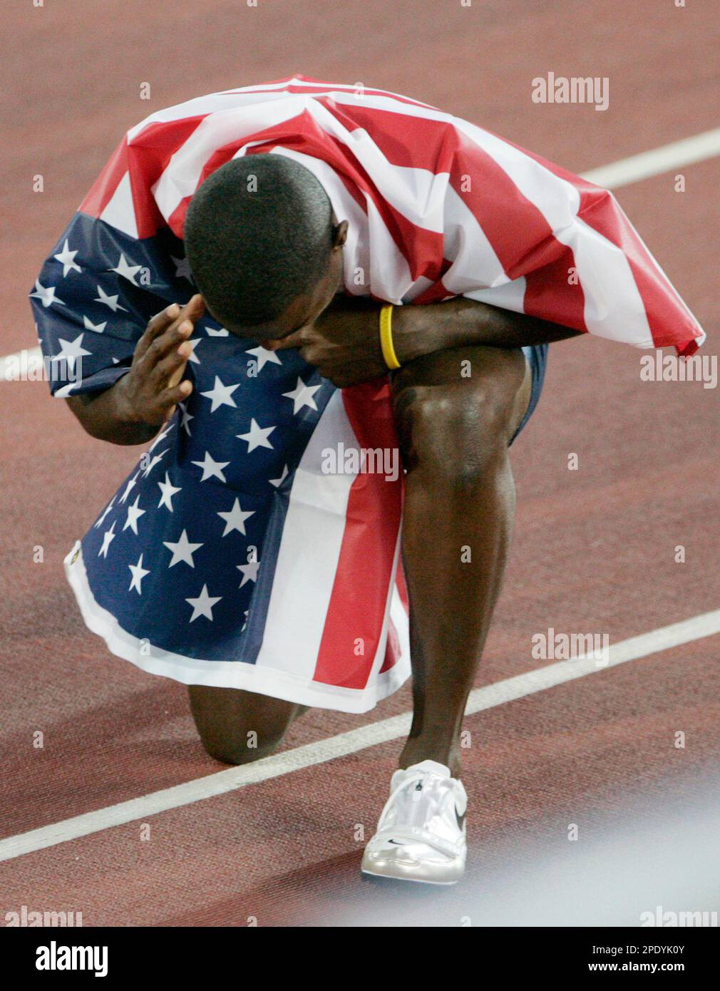 Justin Gatlin of the US kneels on the track wrapped in the Stars and ...