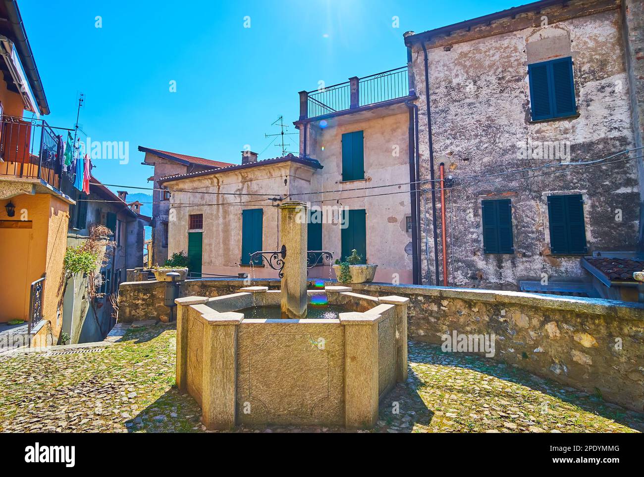 The medieval stone fountain and historic housing on Piazza Rusciett ...