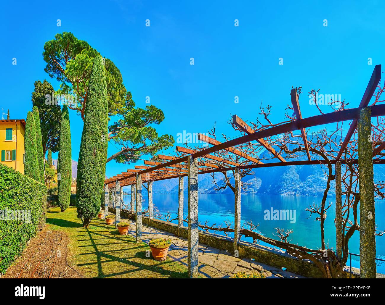 Panorama of the green garden with a vintage stone-wooden pergola ...