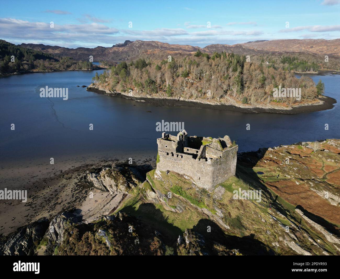 Aerial view of Tioram Castle perched atop a hill surrounded by green ...