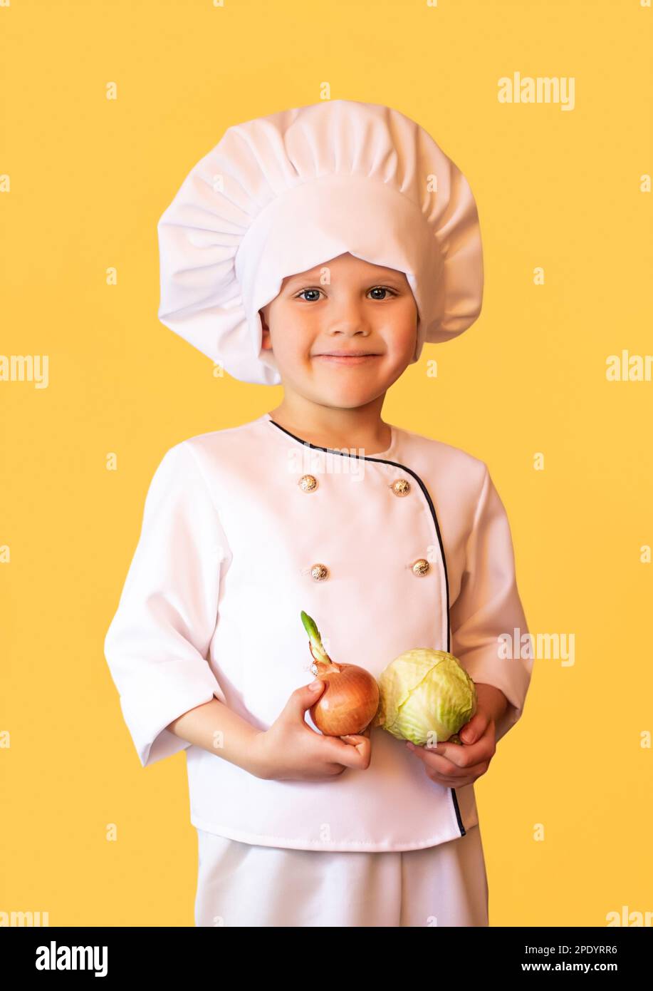 Cheerful boy in chef uniform with vegetables in his hands Stock Photo ...