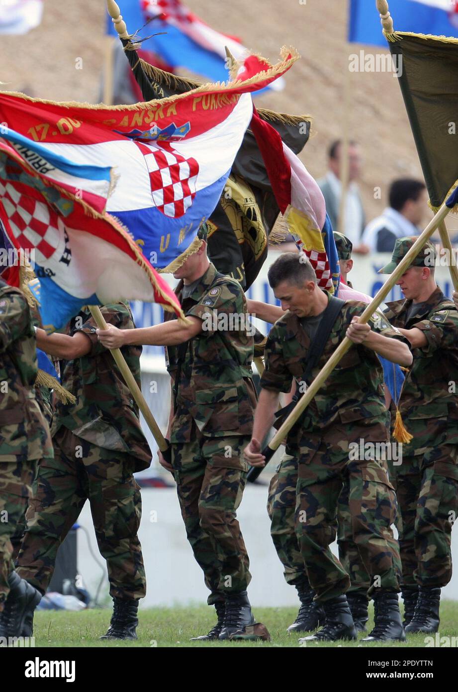 Croatian soldiers fight the strong wind as they carry their unit's ...