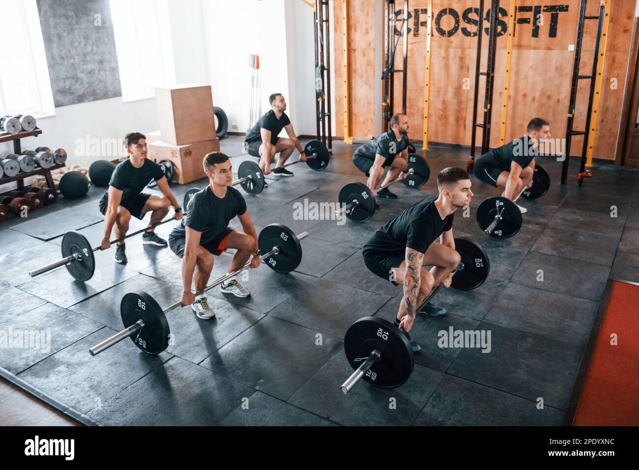 Busy by doing exercises. Group of young sportive people have crossfit ...