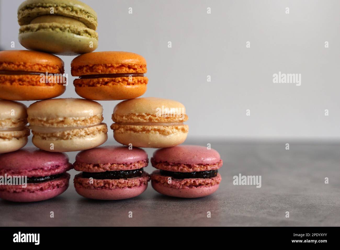 A pile of colorful sweet French macarons against a neutral background ...
