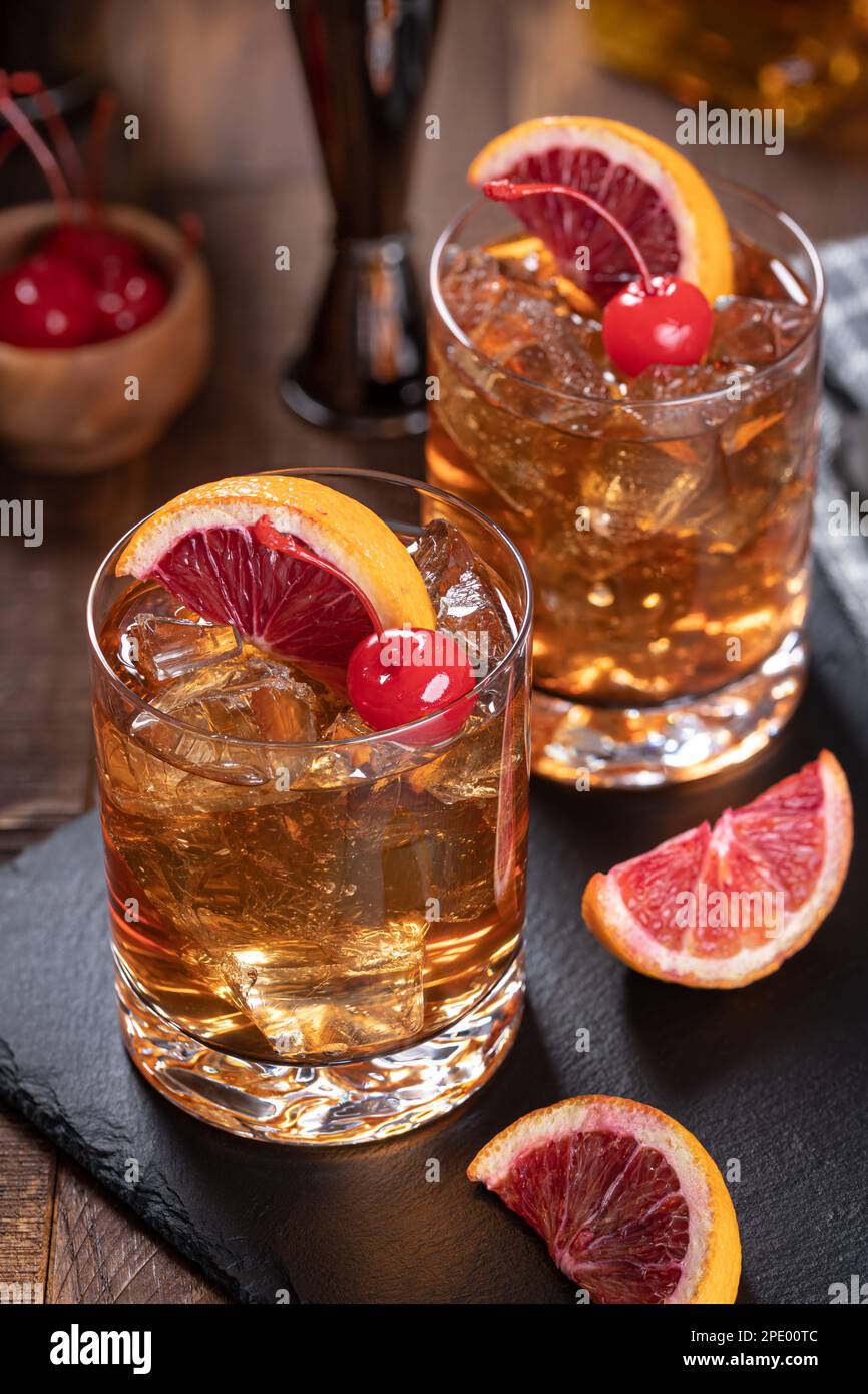Old fashioned whiskey cocktail with cherry and orange slices on a black ...