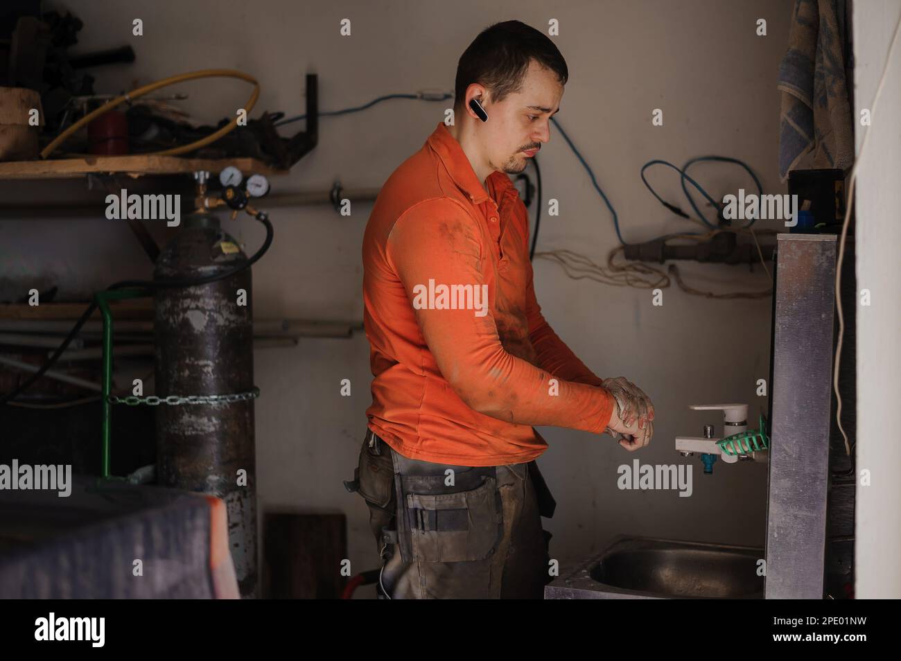 Male auto mechanic washing his hands after car repair. Worker washes ...
