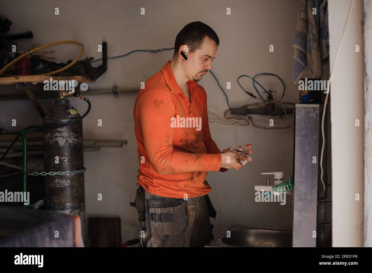 Male auto mechanic washing his hands after car repair. Worker washes ...