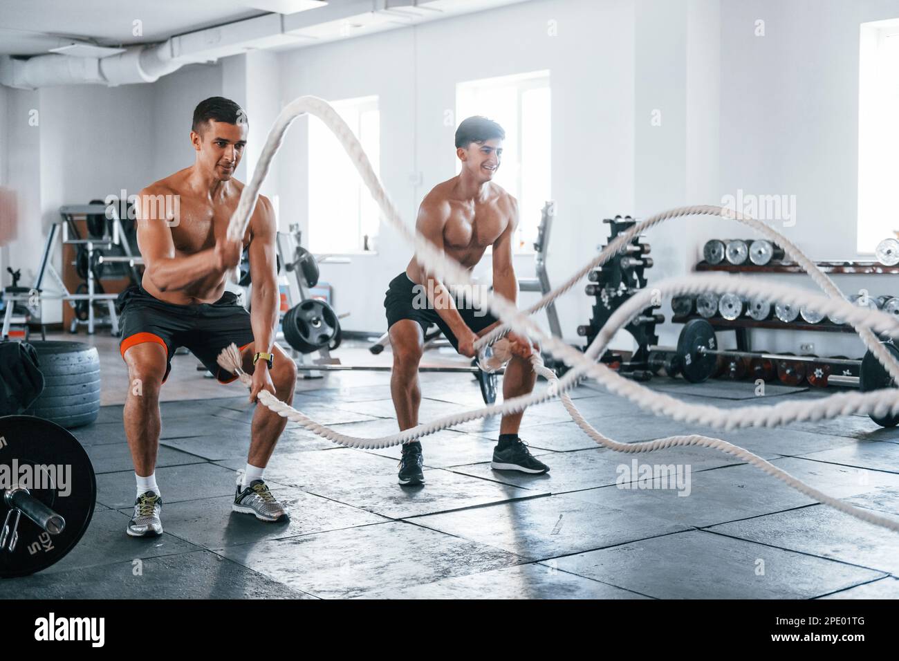 Young people with sportive body shapes doing crossfit by using knots ...