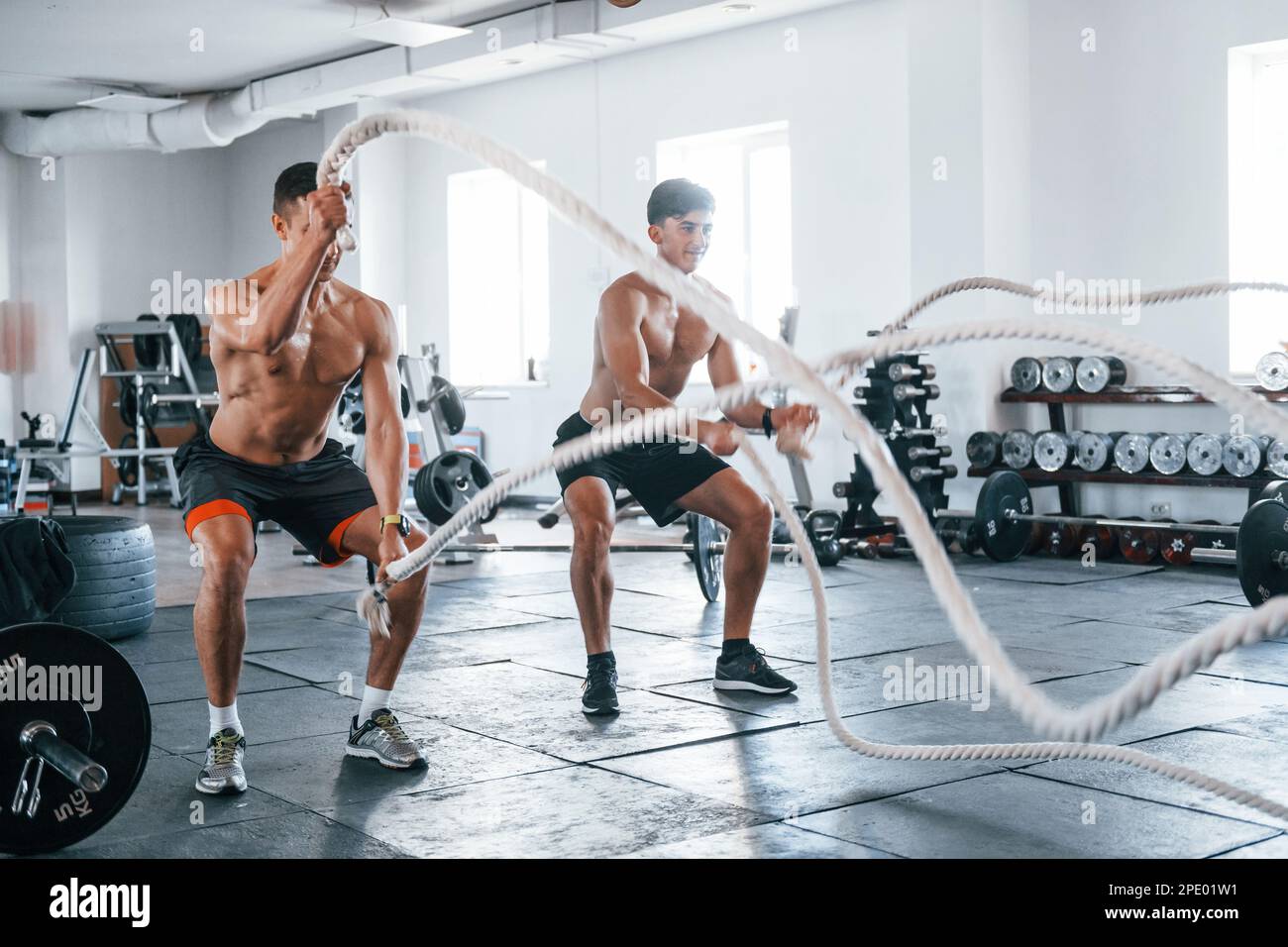 Young people with sportive body shapes doing crossfit by using knots ...