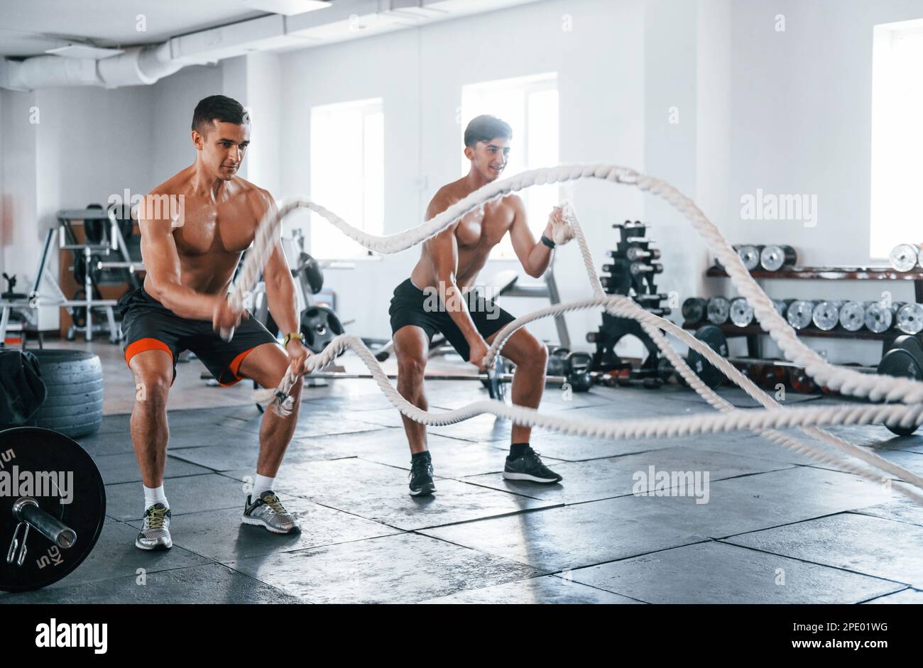 Young people with sportive body shapes doing crossfit by using knots ...