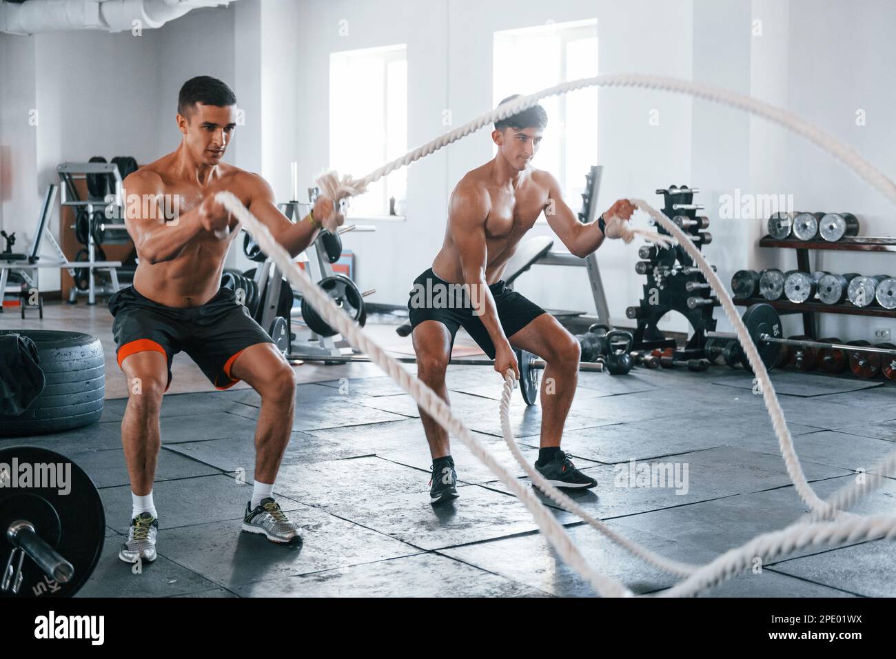 Young people with sportive body shapes doing crossfit by using knots ...