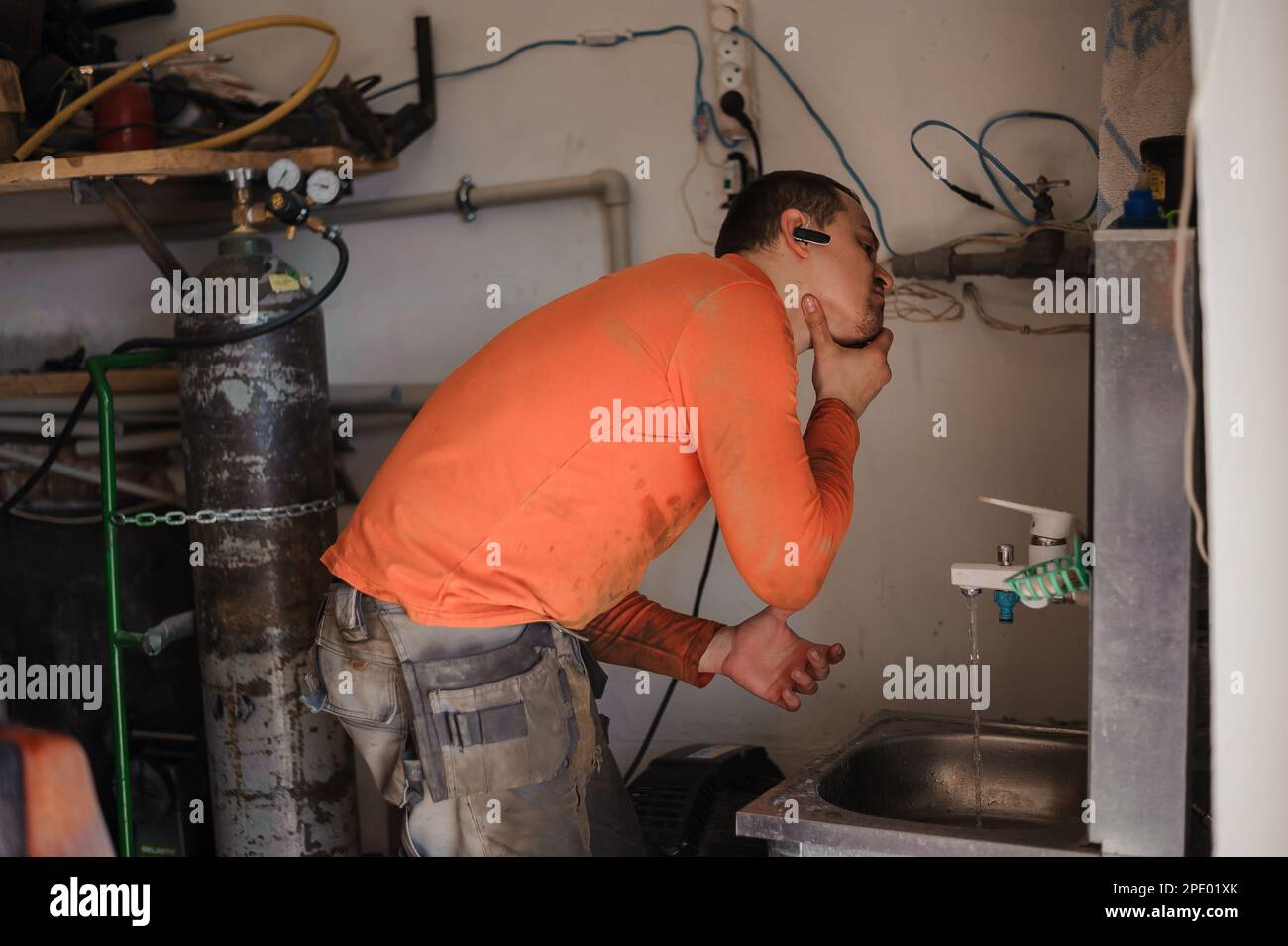 Male auto mechanic washing his hands after car repair. Worker washes ...
