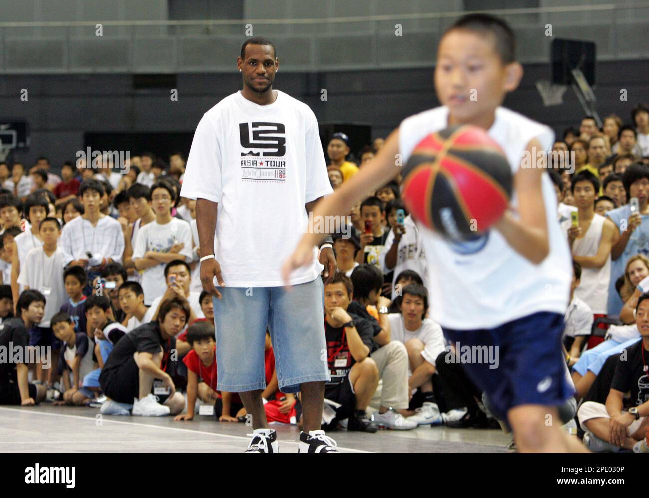 NBA star LeBron James looks on a Japanese boy dribble the ball during ...