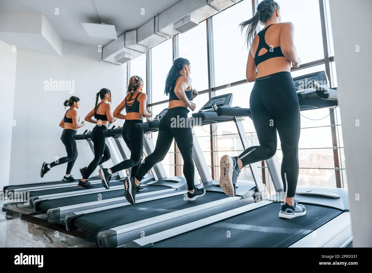 Running on a treadmill. Group of young sportive people have crossfit ...