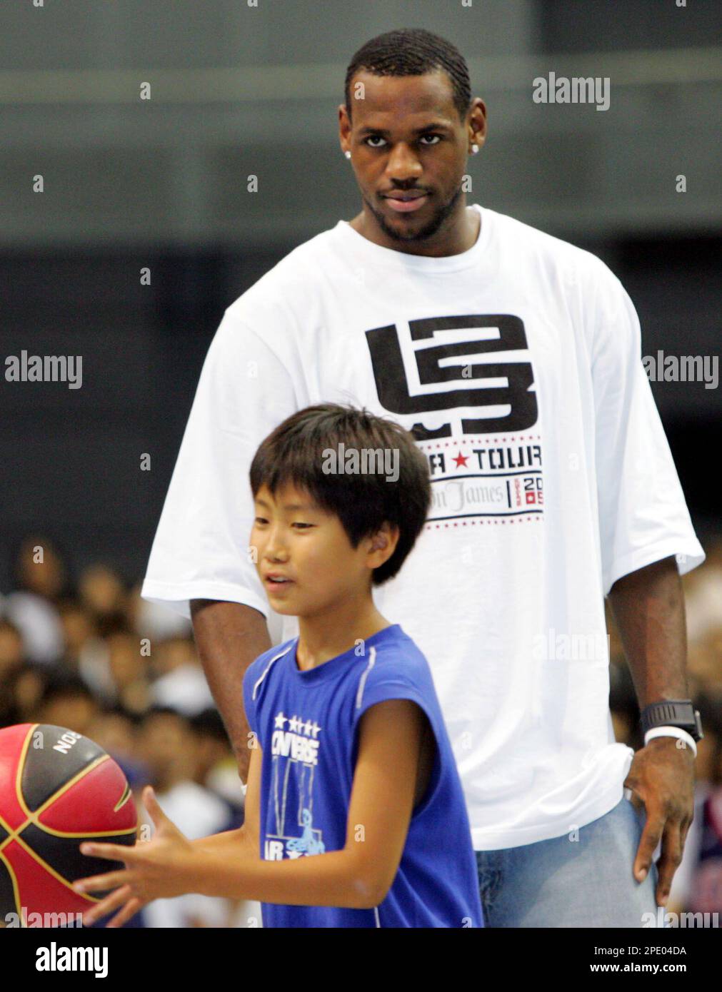 NBA star LeBron James looks on a Japanese boy dribble the ball during ...