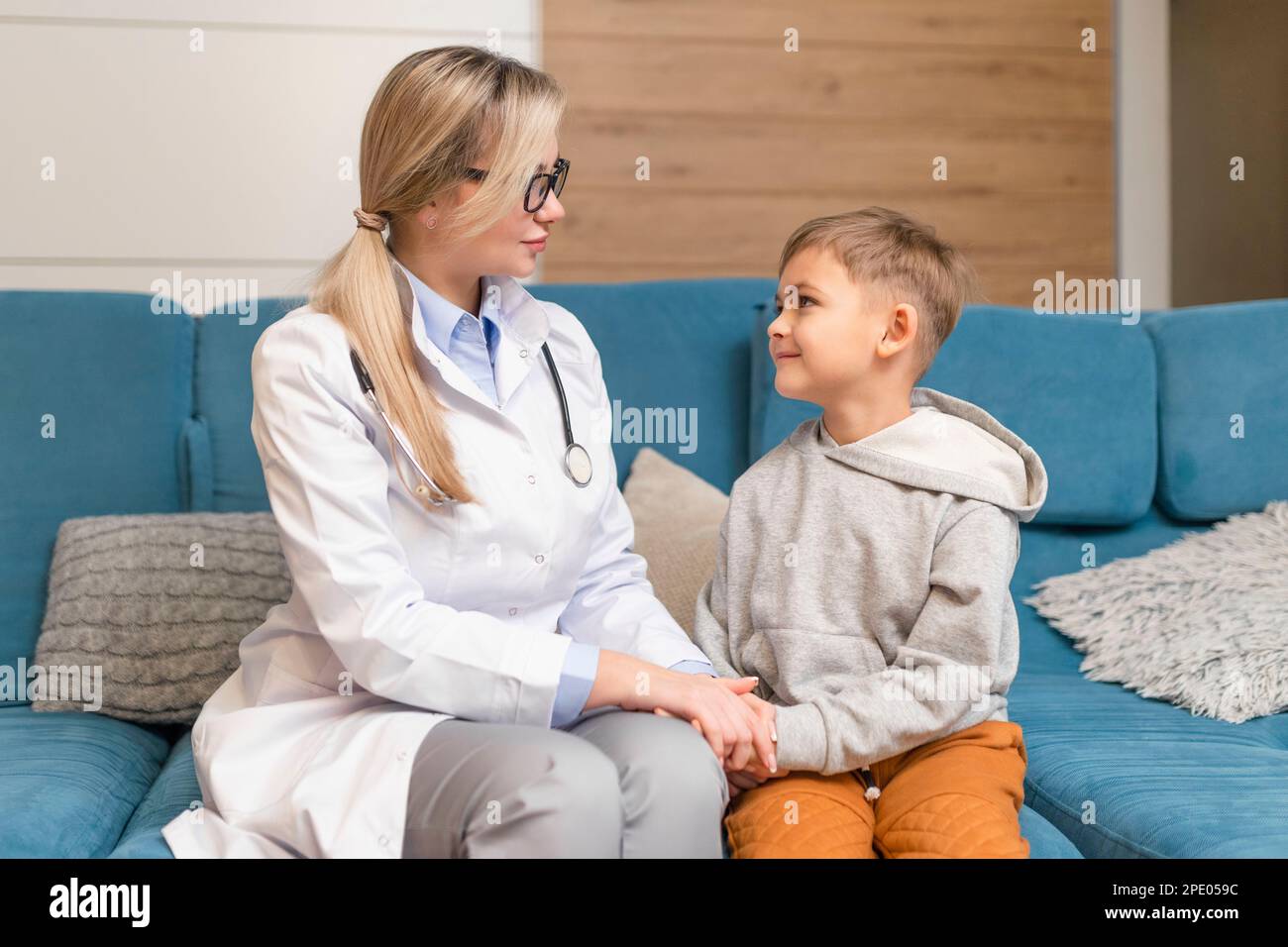A family doctor examines a little boy at home. Pediatrician girl treats ...