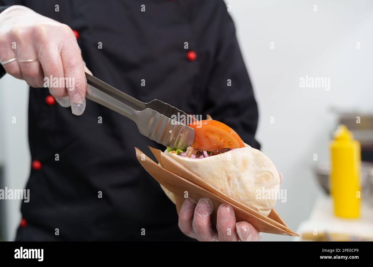 Cook stuffing Greek pita crete sandwich with fresh vegetables. Chef ...