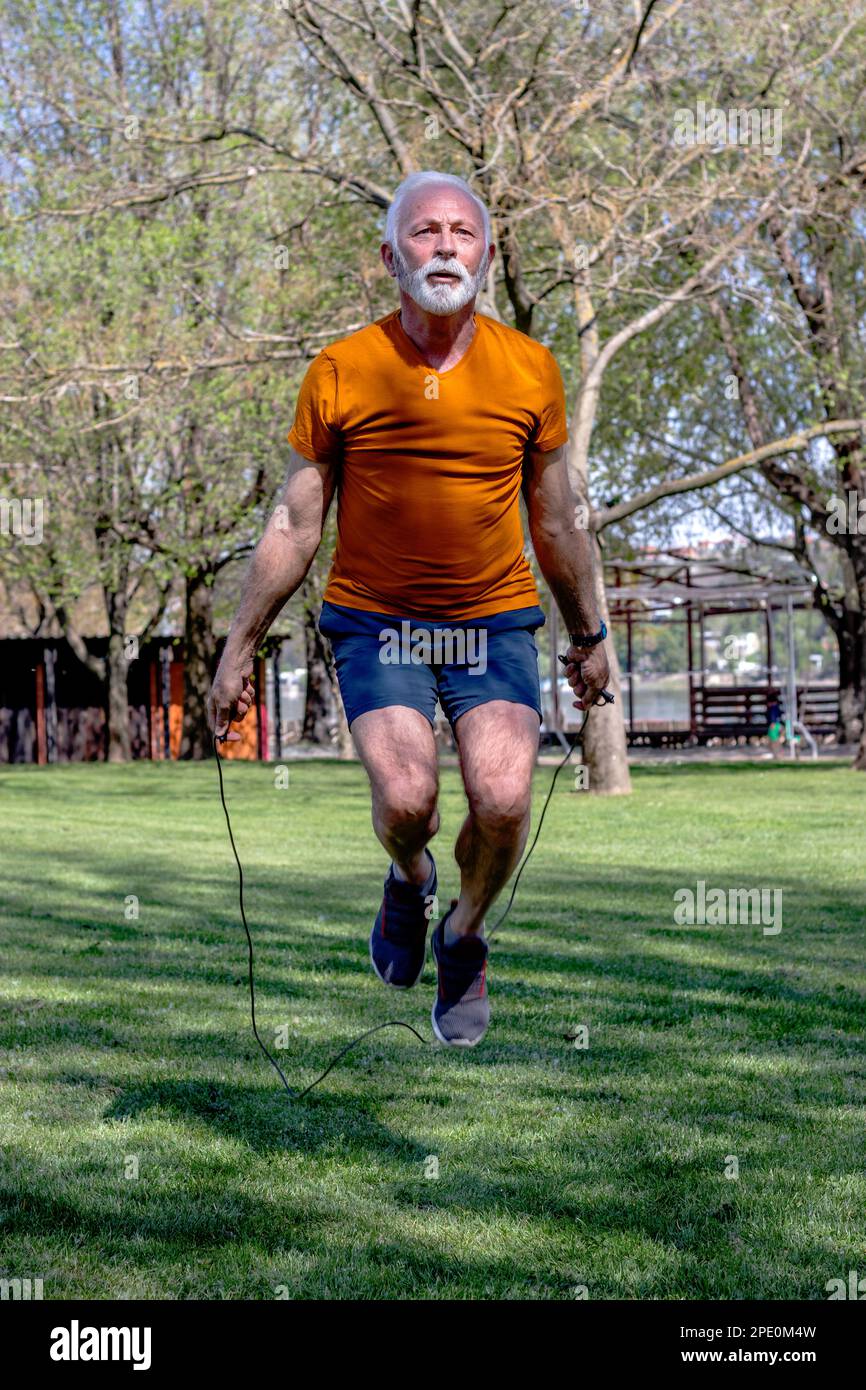 Active senior male jumping the rope. Determined elderly man exercising ...