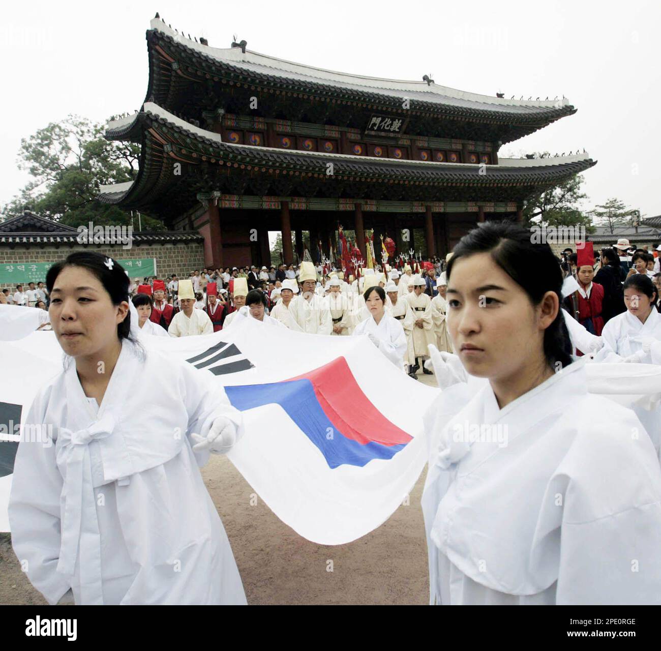 South Korean women in mourners dress, hold a huge national flag as they ...