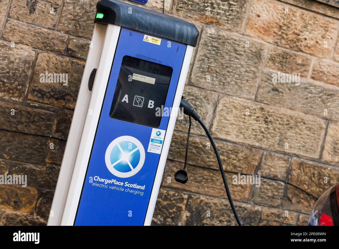 A red electric vehicle plugged in at a ChargePlace Scotland EV charging ...