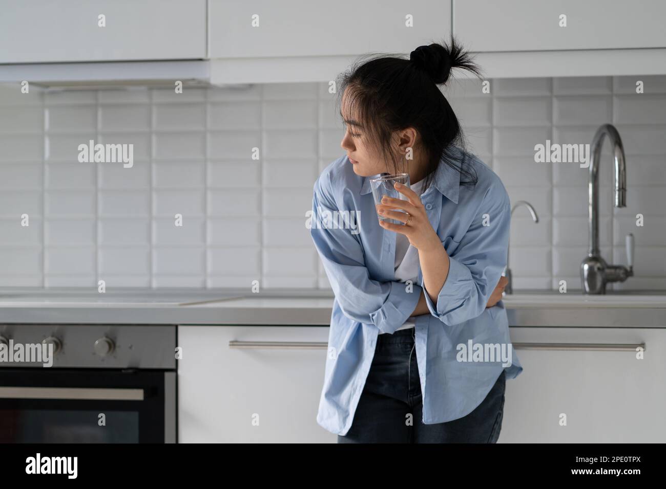 Unhappy suffering Asian woman having digestive problems standing in ...