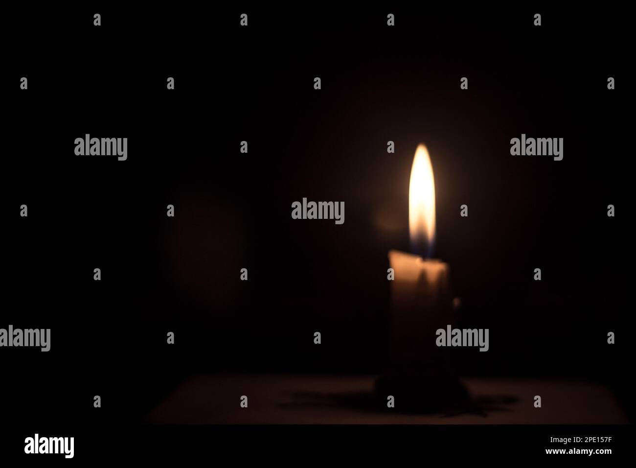 A single candle burning brightly in the dark Stock Photo - Alamy
