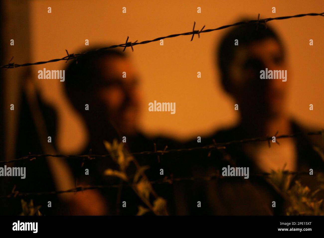 Israeli soldiers stand behind barbed wire at the entrance of Kfar ...