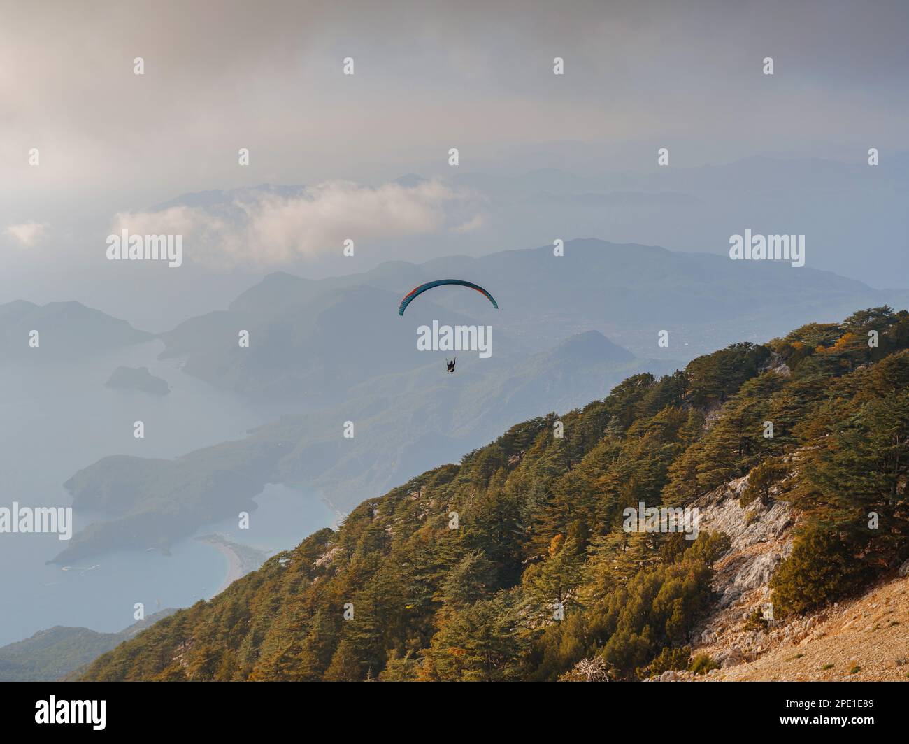 Paragliding in sky. Paraglider tandem flying over sea and mountains in ...