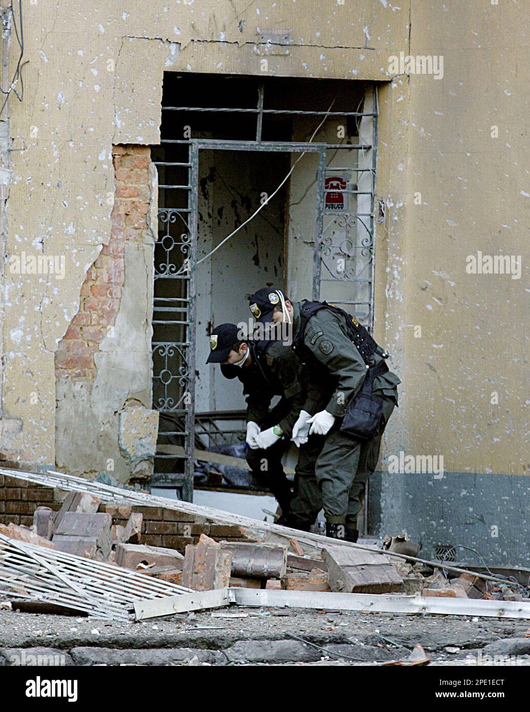 Explosive experts inspect the site where a bomb exploded in front of a temporary shelter for ...