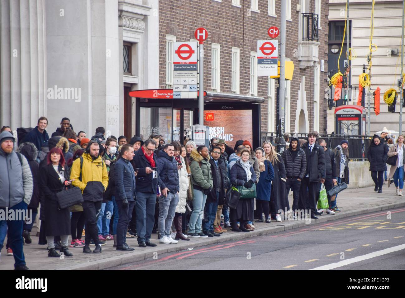 London, England, UK. 15th Mar, 2023. Commuters wait at a bus stop ...