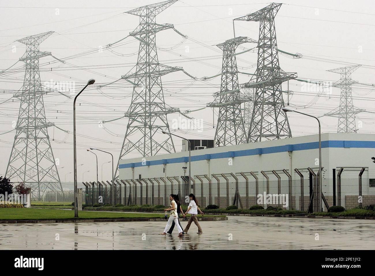 Workers walk past pylons at the Qinshan No. 2 Nuclear Power Plant ...