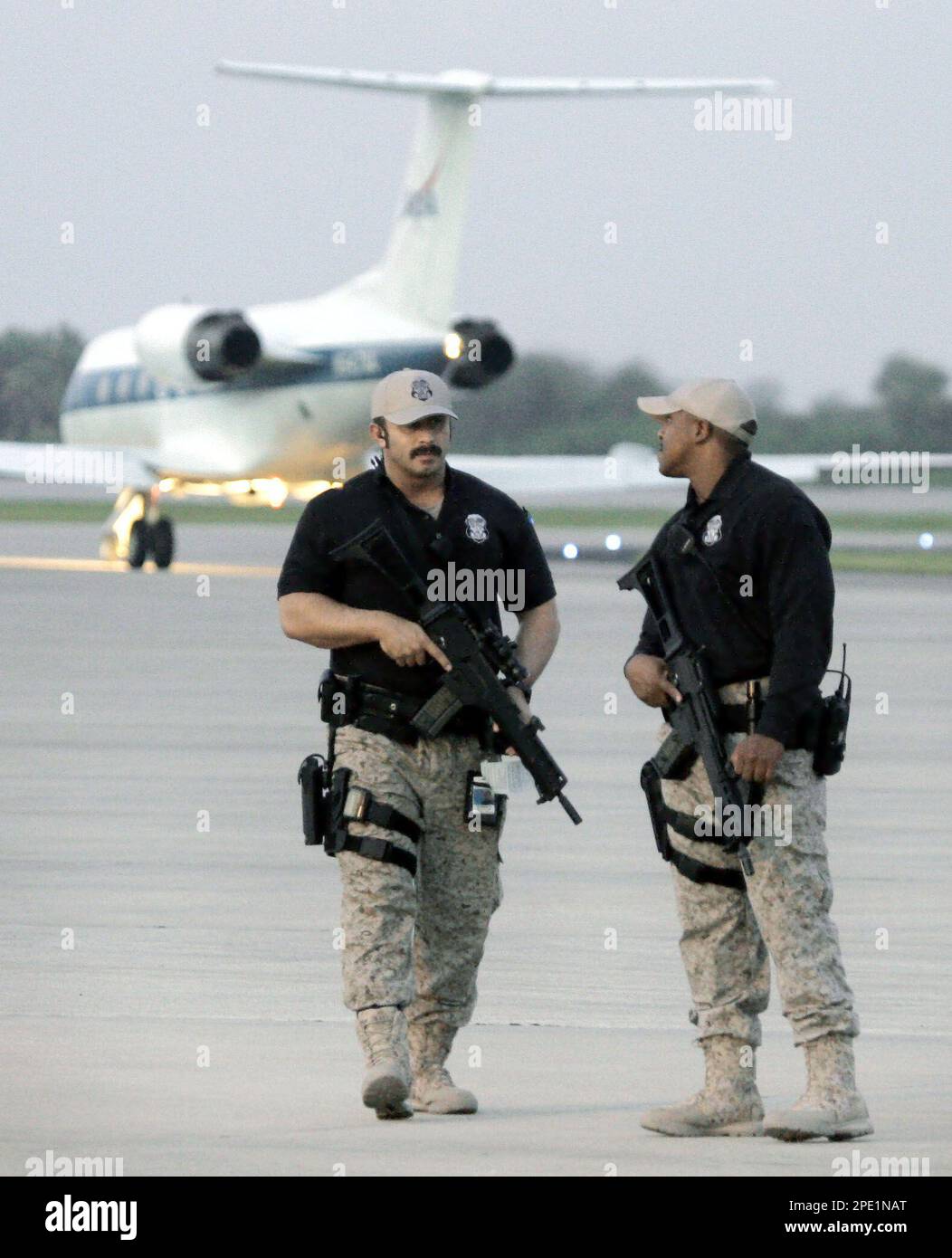 Two NASA SWAT team members stand guard as a Shuttle Training Aircraft ...