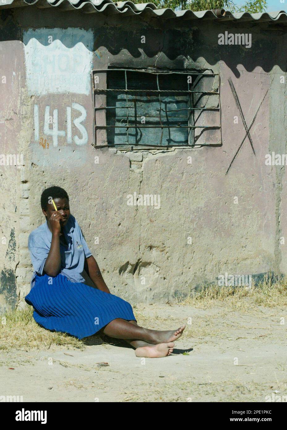 Getrude Majuru sits outside her home in Epworth, Zimbabwe, marked with ...