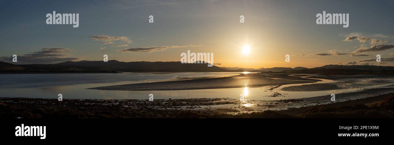 An idyllic scene of a sun setting over a calm body of water in coastal ...
