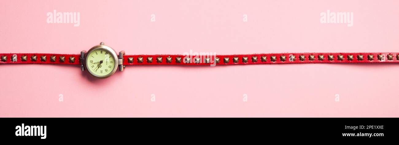 Vintage womens watch with a red long leather strap isolated on pink ...