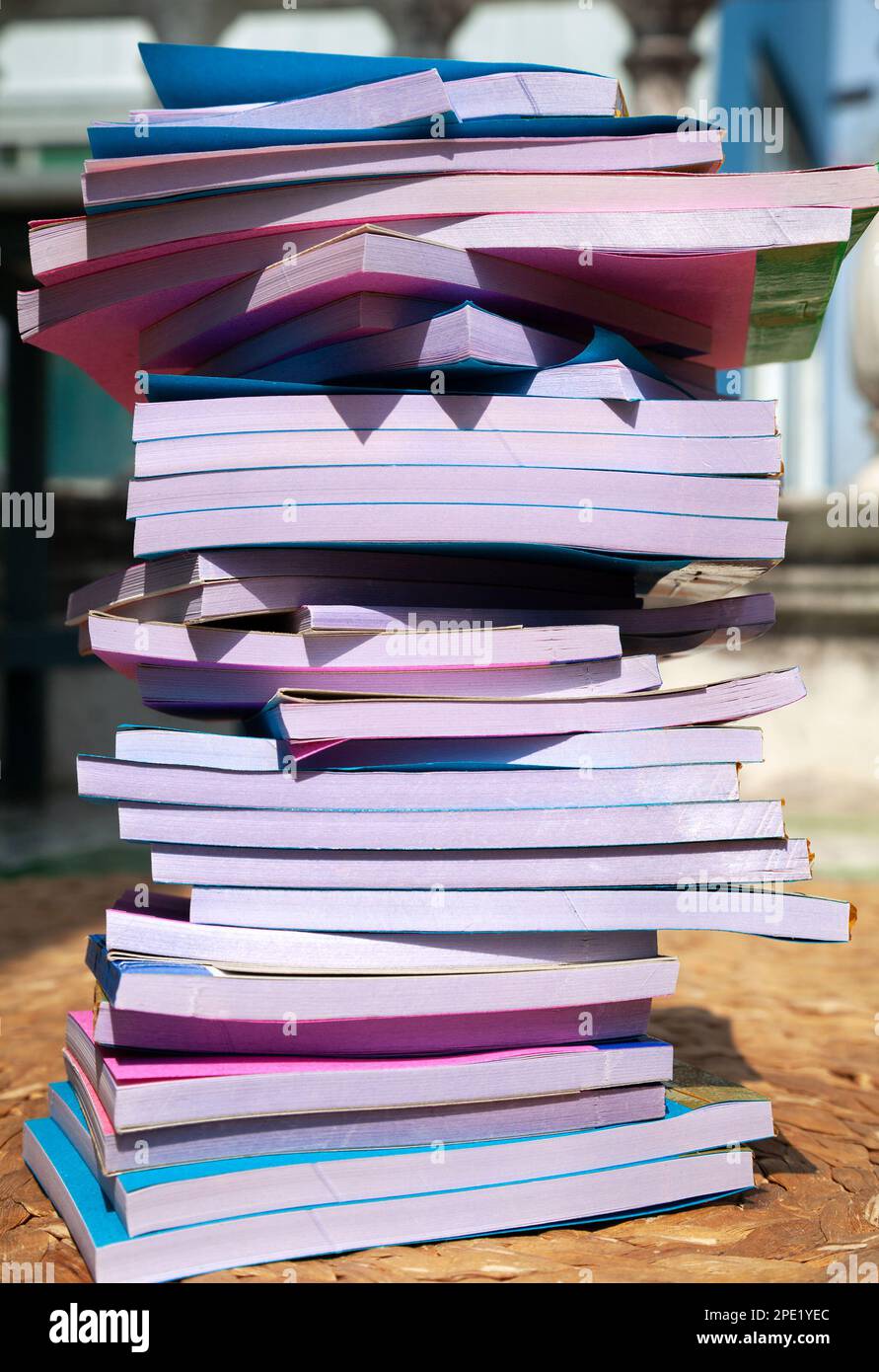 Many cheap small notepads in a messy stack seen from a side. A pile of ...