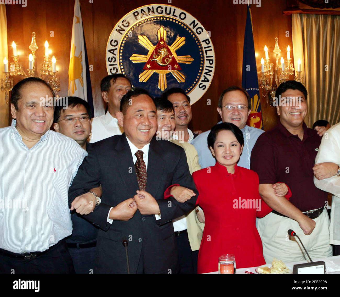 Philippine President Gloria Macapagal Arroyo, in red, links arms with ...
