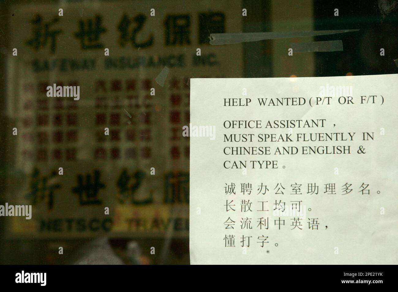 A help wanted sign in english and chinese is taped to the door of a ...