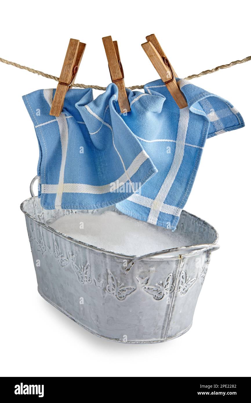 A blue kitchen dishcloth hangs on clothespins over an iron bowl of foam ...