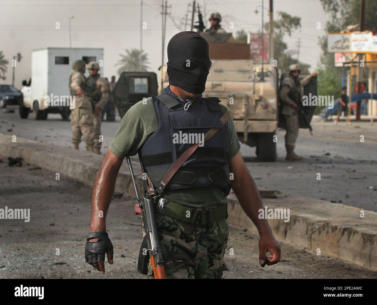 A masked Iraqi soldier arrives at the scene of an attack after a parked ...