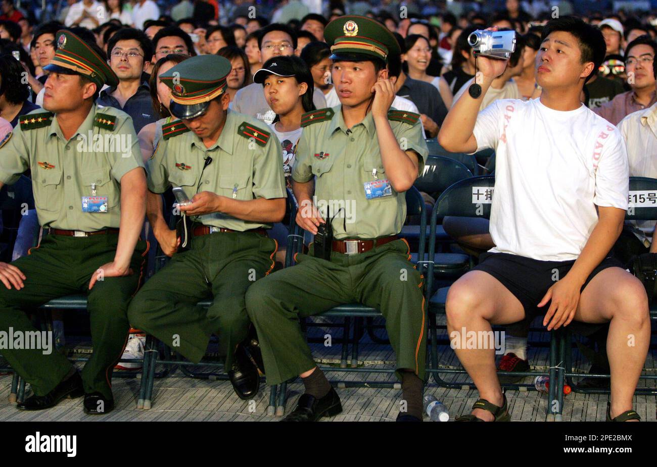 A rock fan films rock and roll singers as Military and police stand ...