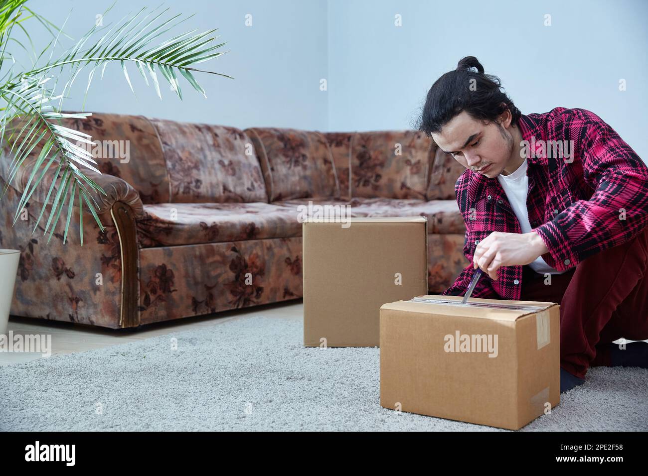 The guy is opening a box of things at new apartment Stock Photo - Alamy