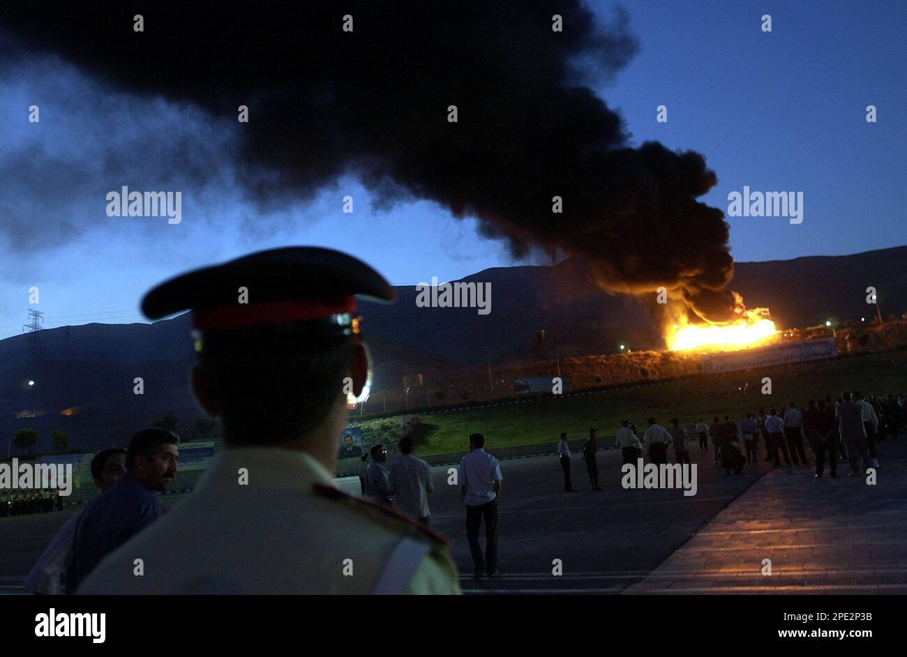 Iranian military police and observers stand to watch the smoke and ...
