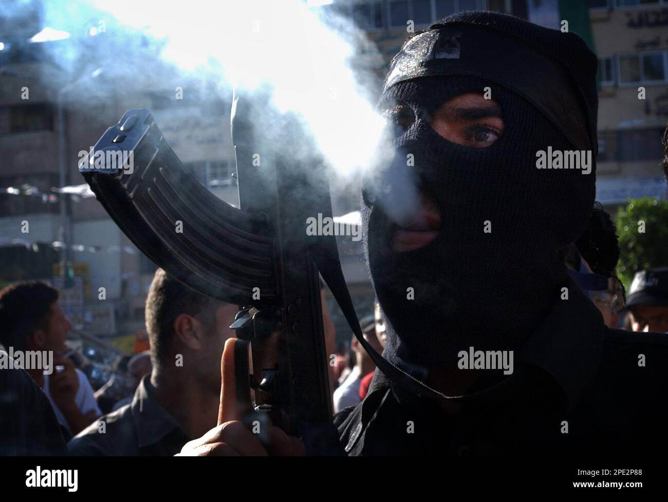 A masked militant blows smoke as he holds his weapon during a rally of ...