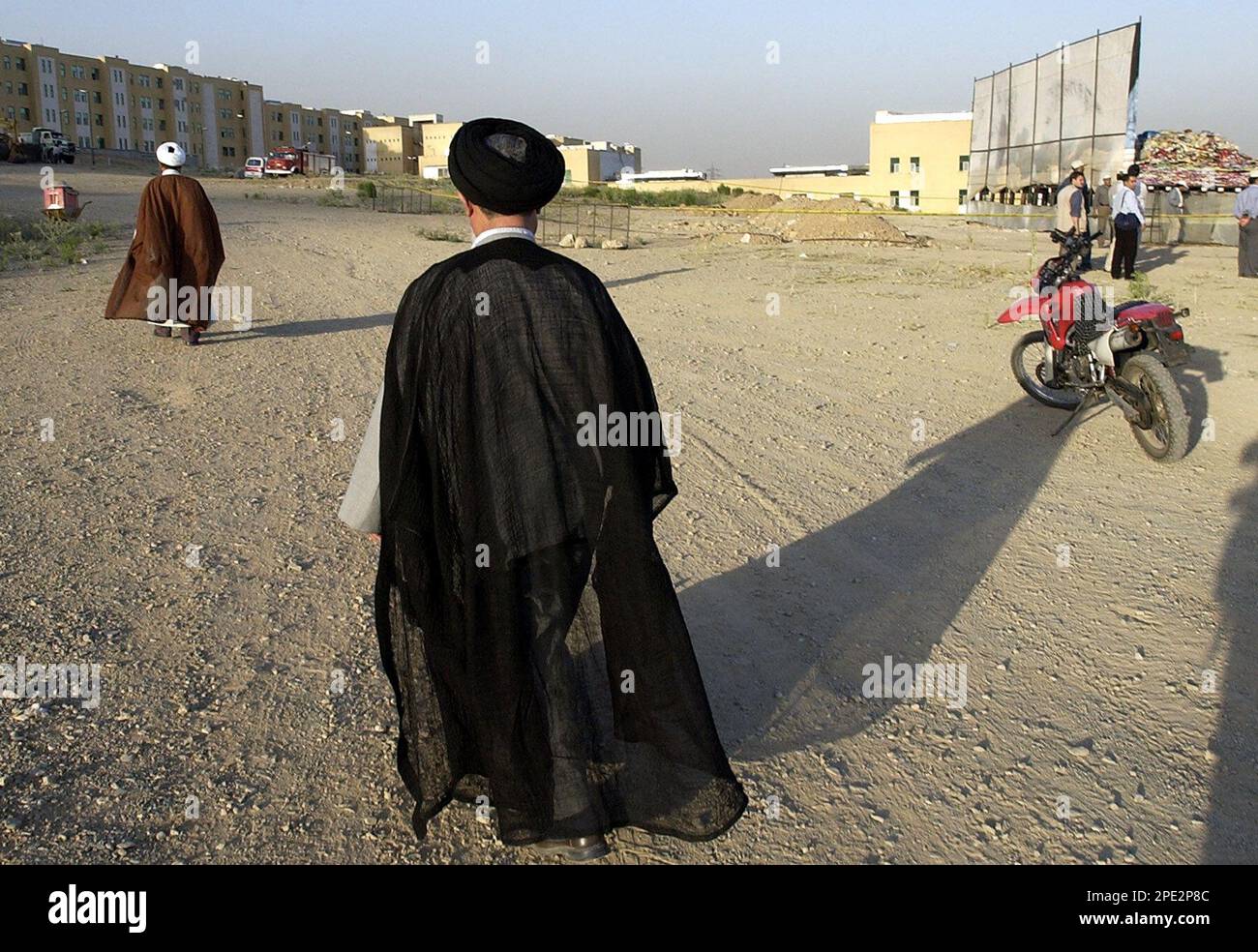 Iranian clerics walk past drugs, at right background, piled high before ...
