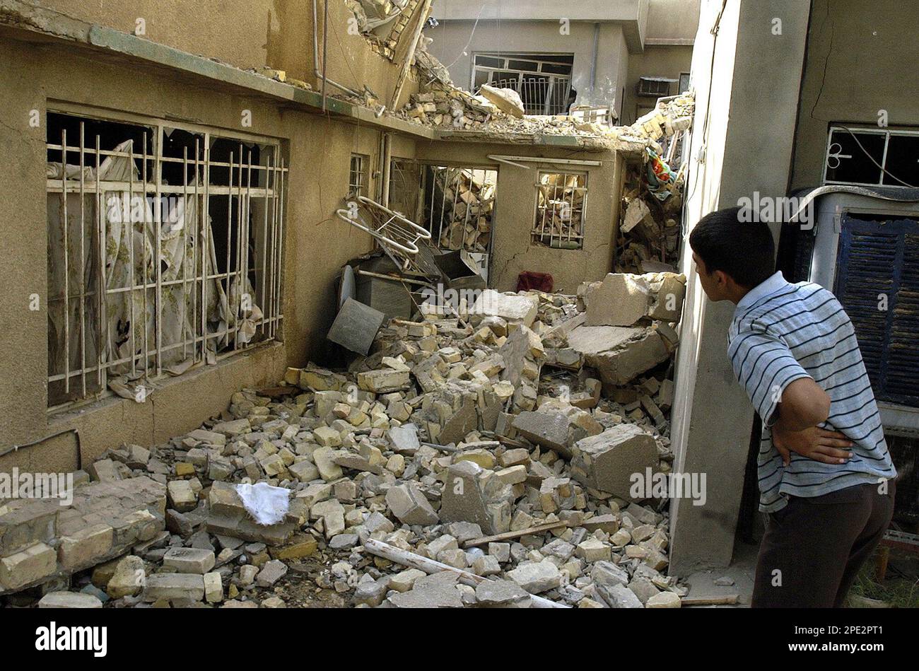 An Iraqi boy looks at the damage to a destroyed house after a mortar ...