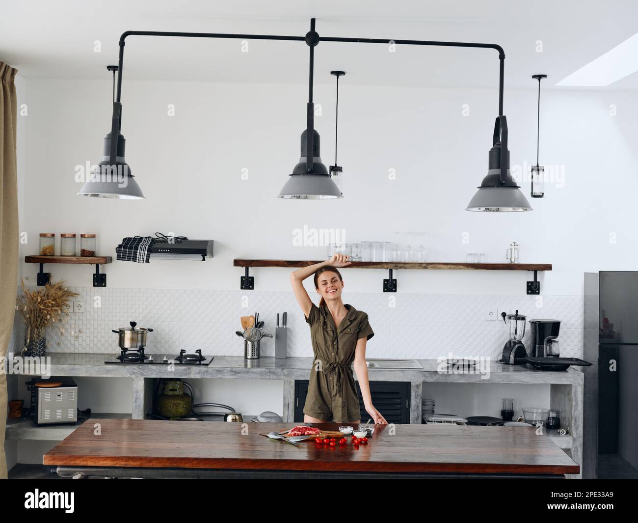 Happy woman chef stands in Stylish minimalist kitchen interior with ...