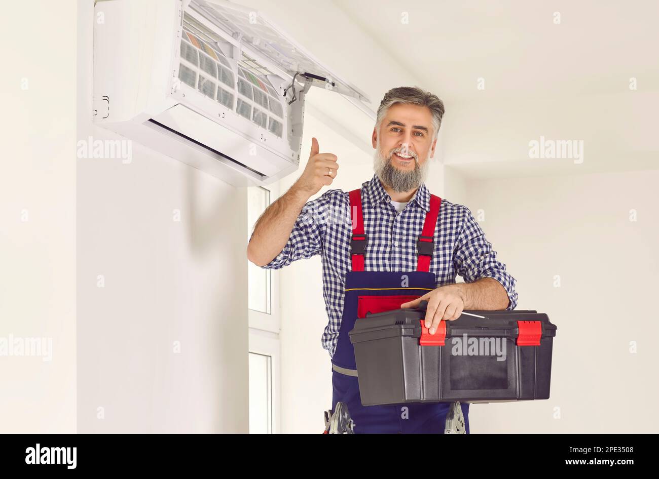 Technician man from AC service installs good modern air conditioner in ...