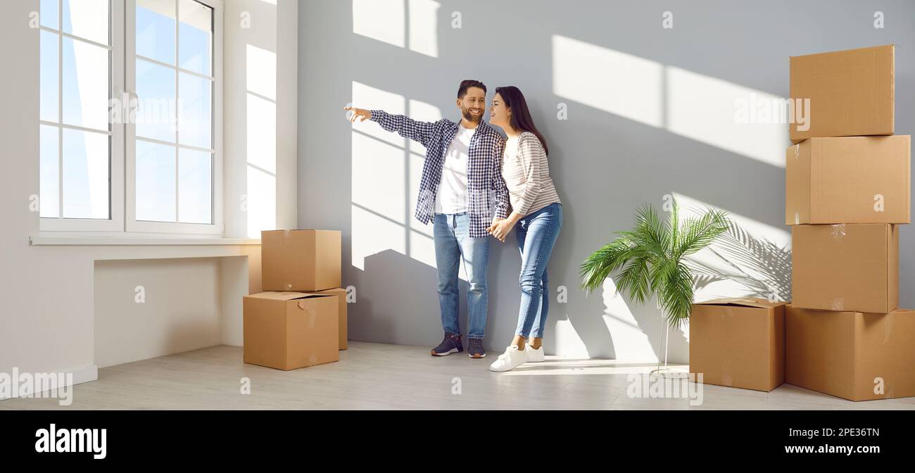 Happy young family couple looking through window in own new home Stock ...