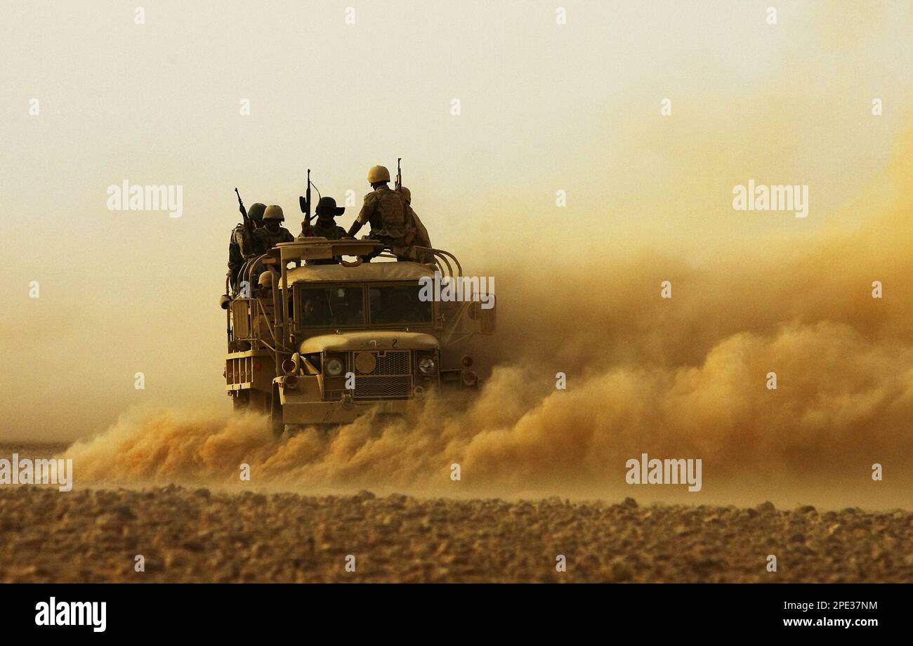 Iraqi soldiers ride through dust in the back of an open truck as they ...